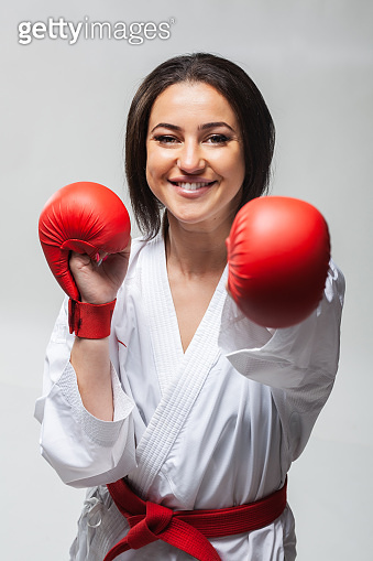 portrait of karate girl in kimono and red gloves giving kick towards ...