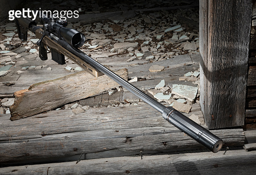 Bolt action rifle with a suppressor in an abandoned building ...