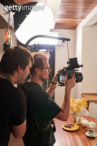 Young videographer and his assistant preparing video camera for ...