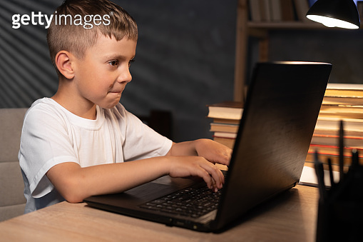 Portrait of child schoolboy studying at home using laptop computer at ...