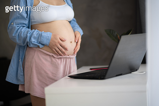 Pregnant woman using laptop at home. pregnant belly of expectant mother ...