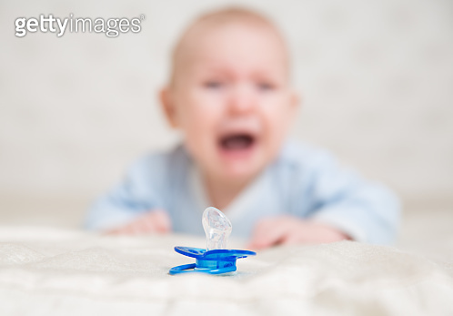 Kids Pacifier in front of crying Baby. Soother and upset Infant Child ...