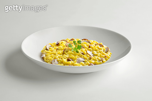 Yellow risotto with saffron, porcini mushrooms and parsley in white ...