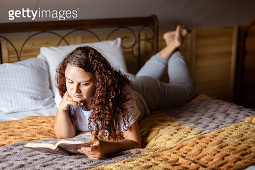 Caucasian brunette woman lying on belly with legs crossed up on double ...