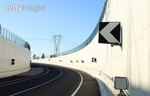 Road curve at the exit of an underpass with high white concrete wall ...