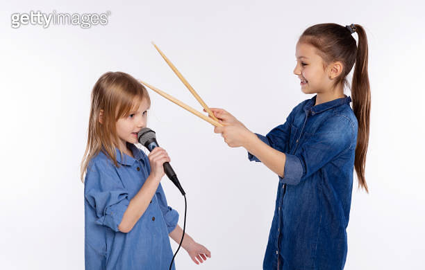 Rock and roll music concept. Two girls 6 and 8 years old sing in a ...