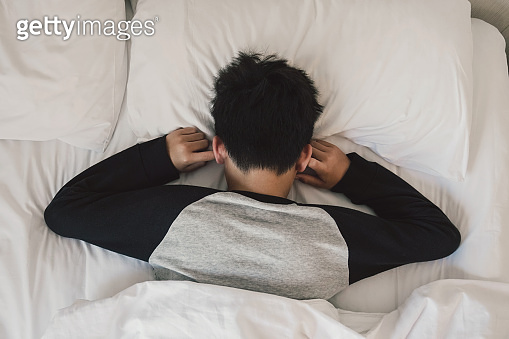 Preteen tween boy covering ears with his fingers in bed, ADHD, sleep ...