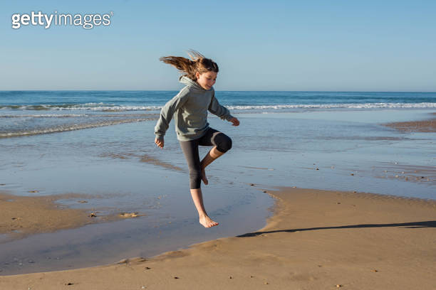 pretty girl on beach holiday playing and jumping barefoot on the sand ...