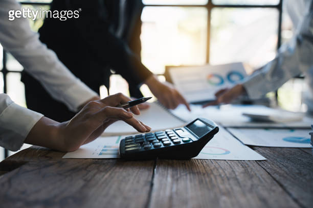 Team working on business project at messy table with graph chart and ...