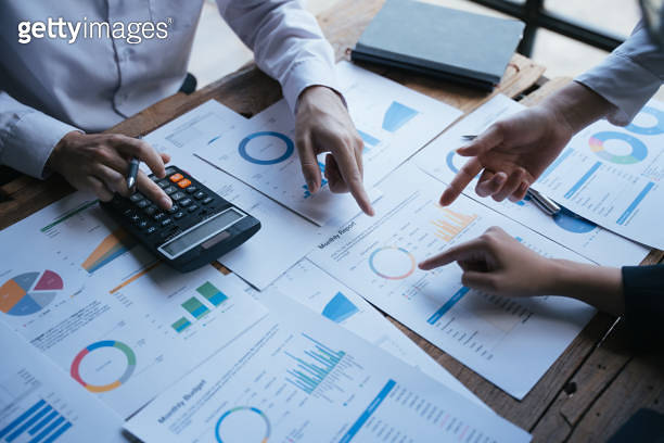 Team working on business project at messy table with graph chart and ...