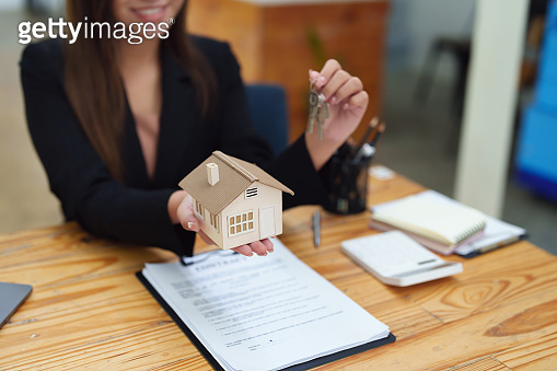 Asian female bank employee handing over a house and keys to a client ...