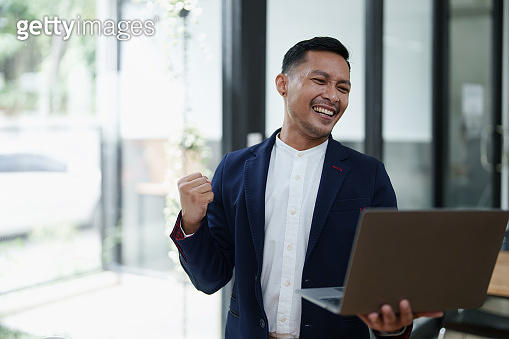 Portrait of an Asian male business owner standing with a computer ...