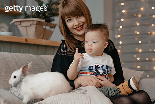 Mom holds her son with Down Syndrome in her arms while sitting on the ...