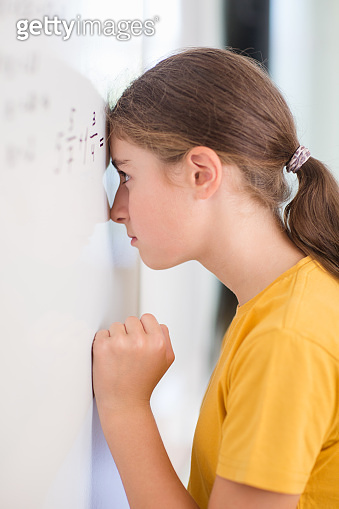 frustrated tired student is standing at blackboard and can't solve math ...