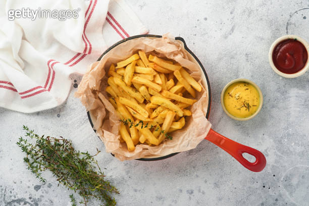 French fries. Tasty French fries server in red cast iron skillet with ...
