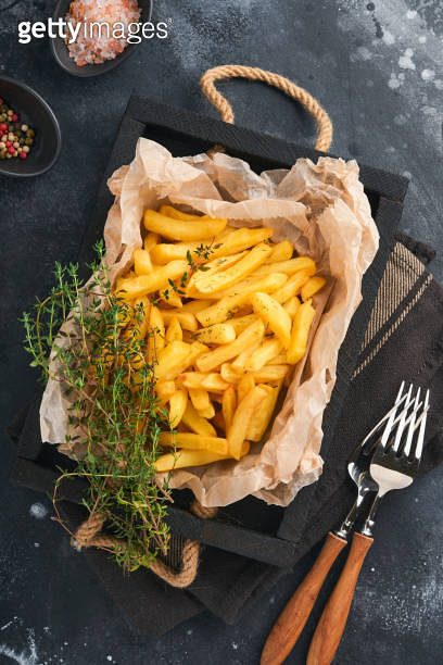 French fries. Tasty French fries server on parchment paper on wooden ...