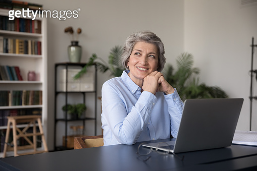 Happy older woman sit at workplace desk looking into distance 이미지 ...