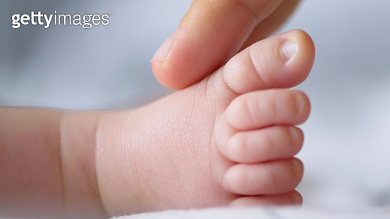 Macro shot of infants toe. Mother touching her small child's toes while ...