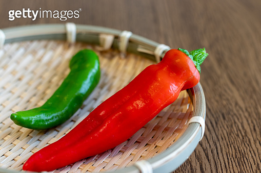 Red chili pepper and shishito green pepper on a bamboo colander ...