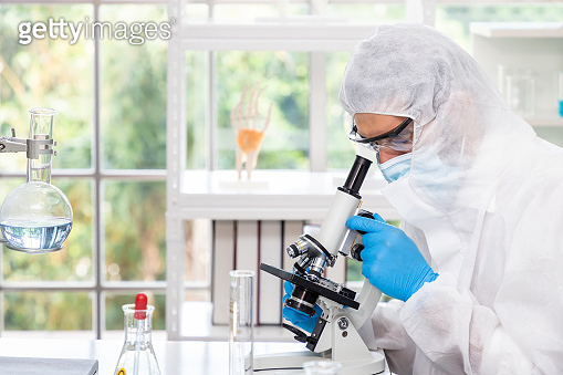 Researcher in laboratory personal protective equipment suit or PPE ...
