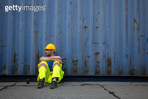 worker wearing safety helmet is taking rest and thinking of something ...
