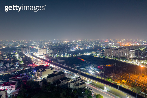 elevated metro track going across the screen over a lit road surrounded ...