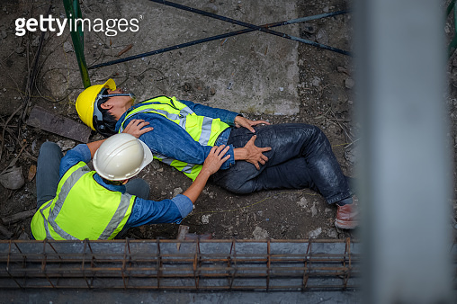 A young Asian builder falls from a scaffold at a construction site. An ...