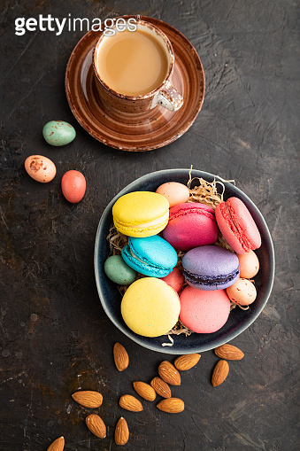 Different colors macaroons and chocolate eggs in ceramic bowl, cup of ...