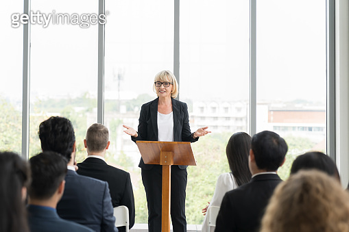 Senior business woman talking at podium speaker. Senior business woman ...
