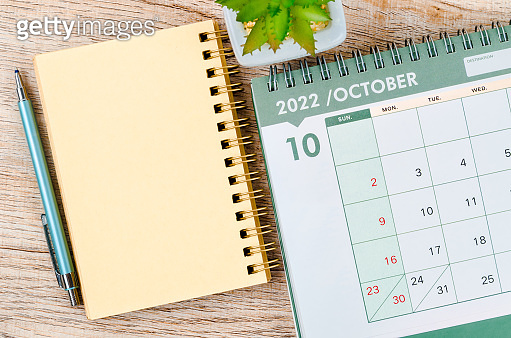 October 2022 desk calendar and diary with small plant on wooden ...