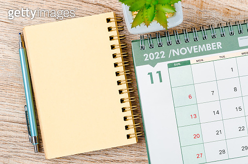 November 2022 desk calendar and diary with small plant on wooden ...