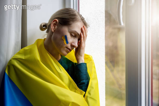 sad worried woman with ukraine flag sit on window sill. solidarity and ...