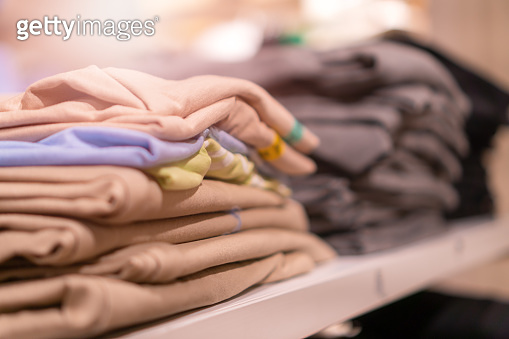 Selective close-up focus of a stack of light clothes on a shelf in a ...