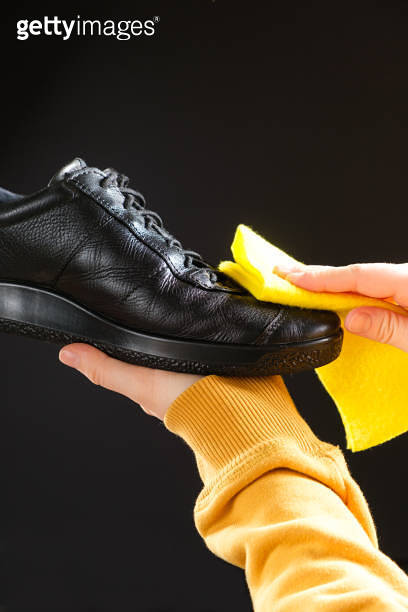 A man wipes leather men's black shoes with a yellow shoe rag. 이미지 ...