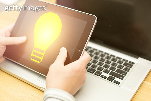 hand hold tablet with light bulb idea illumination in business ...