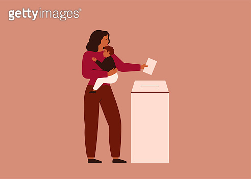Mother holds baby putting election ballot into box on voting station ...