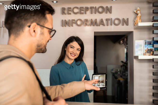 Smiling male receptionist behind the hotel counter showing guest ...