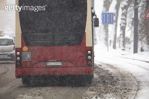 Bus public transportation driving on snowy streets in winter conditions ...