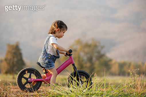 Happy child riding a bike. Little girl on a pink bicycle. Healthy ...