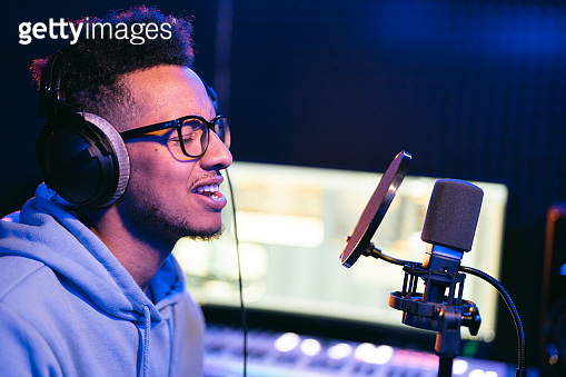 Young male singer in recording studio performing in neon lights ...