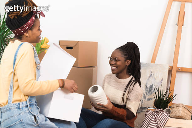Two African roommates having fun while moving in and unpacking ...