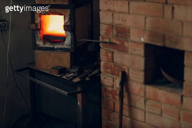 Blacksmith forge oven with hot flame. Smith heating iron piece of steel ...
