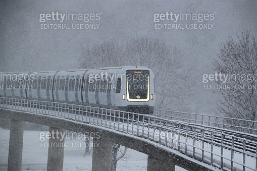 Modern subway bombardier C30 train going over a bridge in heavy snow ...
