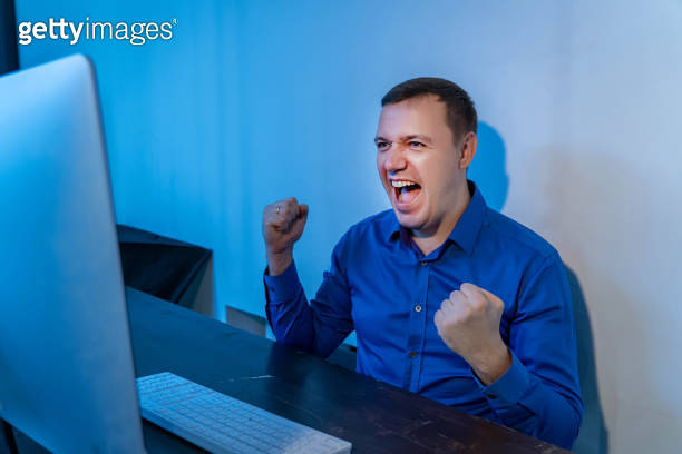 Happy person looks at computer monitor and celebrates his success ...