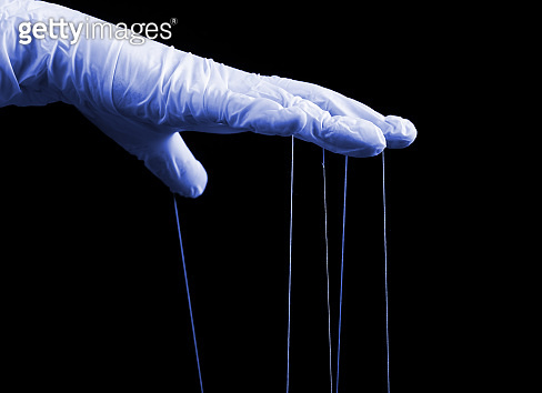 Hand in medical glove with strings on fingers. Manipulation, deception ...