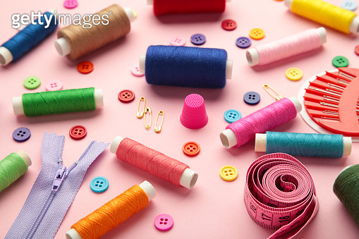 Sewing supplies on pink background: sewing thread, scissors, a large ...