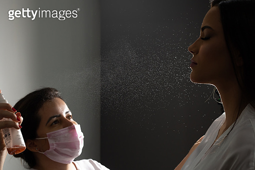 A makeup artist spraying a young woman's face. 이미지 (1397923488) - 게티이미지뱅크