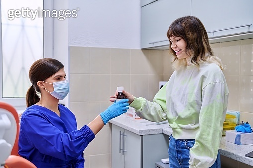 Dentist giving medicine for teeth and oral cavity in bottle to young ...