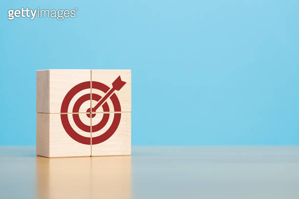 Wooden blocks with red target icon on wooden table blue background copy ...