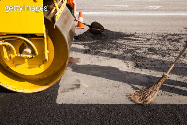 Pavement machine laying fresh asphalt or bitumen on top of the gravel ...
